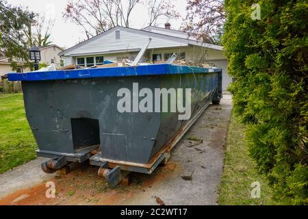 Green dirty trash dumpster, front view, next to the wall of the old ...