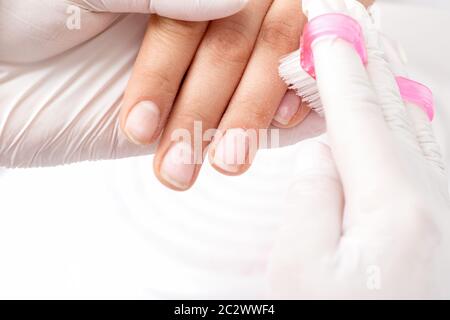 Manicure master removes dust from nails with a brush to cleaning nails ...
