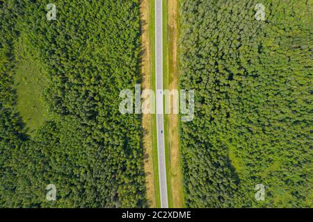 Aerial view of ground road with moving cars in green fields with ...