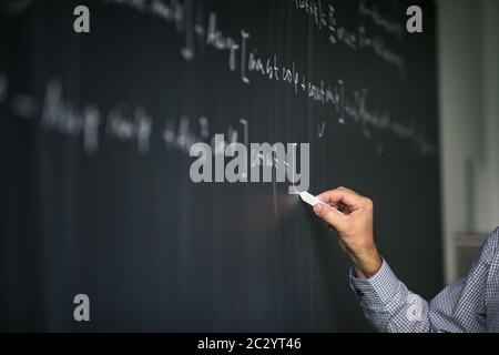 Math teacher by the blackboard during mathclass - detail of the hand ...