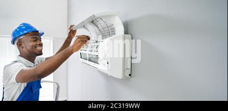 African-American electrician repairing air conditioner indoors Stock ...