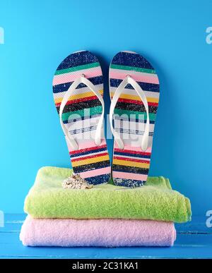 pair of female beach slippers and a towels on a blue background ...