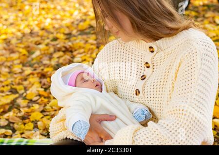 mom holds a baby in her arms in a santa costume on the background of a ...