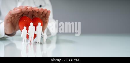Close-up Of A Doctor's Hand Protecting Family Cut Out With Red Heart ...