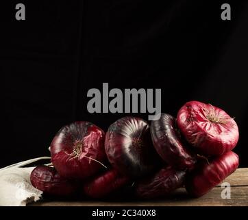 round red onion in husk on a gray linen napkin, black background, close ...