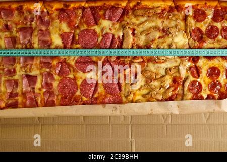 Long big sausage pizza. Measure pizza length with a tape measure Stock ...