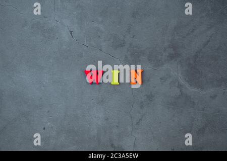 The multicolored win word is made of wooden letters on a grey plastered ...
