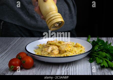 A Closeup of a plate of shrimp alfredo sprinkled with basil sprinkles ...
