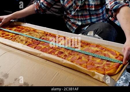 Long big sausage pizza. Measure pizza length with a tape measure Stock ...