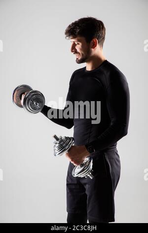 Happy man working out with dumbbells over gray background Stock Photo ...