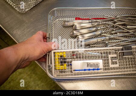 a hand reaches into a sieve with cleaned surgical instruments Stock ...