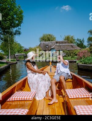 Giethoorn Netherlands couple visit the village with a boat ,view of famous village with canals ...