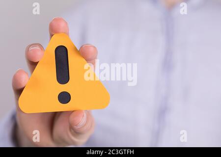 Man holding a yellow triangular warning sign Stock Photo - Alamy