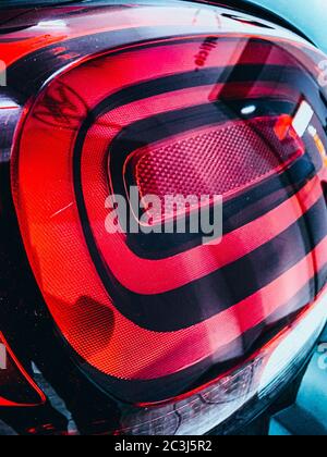 A vertical closeup shot of a rear light of a modern blue car in the ...