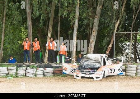 A burnt out car on a gravel road. The rescue service on site to put out ...