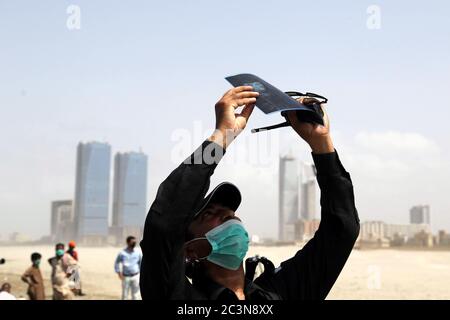 A Pakistani holds x-ray sheet to observe the partial solar eclipse at ...