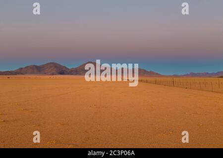 Fence disappearing in the distance in the desert Stock Photo - Alamy