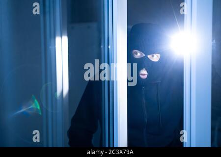 Scared thief breaking into apartment to steal, using torch Stock Photo ...