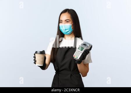 Smiling asian girl barista, cafe staff pouring steamed milk in coffee ...