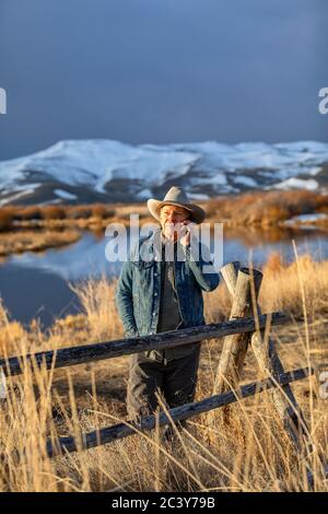 Man in sun hat using smartphone while sitting in outdoor cafe in the ...