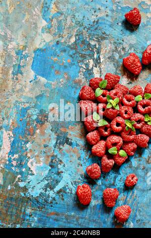 Heart shape made of premium raspberries on a blue background. Close up ...