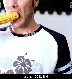 Young man (sliced) eats corn on the cob - grill party Stock Photo - Alamy