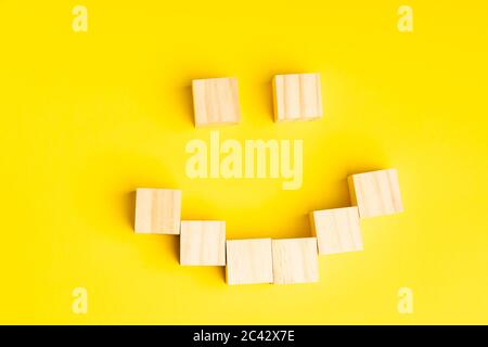 wooden blocks forming a smiling face against yellow background with ...