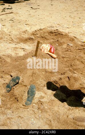 Boy buried in sand Stock Photo - Alamy