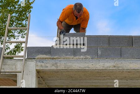 Bricklayer putting down another row of bricks in site during the ...