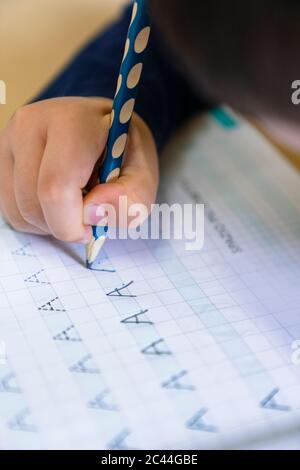A child hand is writing with pen on a spiral notebook on white ...