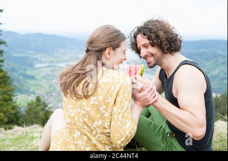 couple in love enjoying watermelon while sitting on the wooden bridge ...