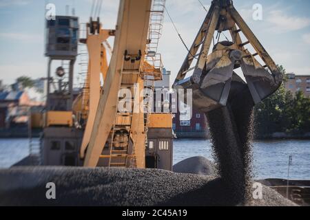 Bulk-handling crane unloading sand, road metal and gravel from cargo ...