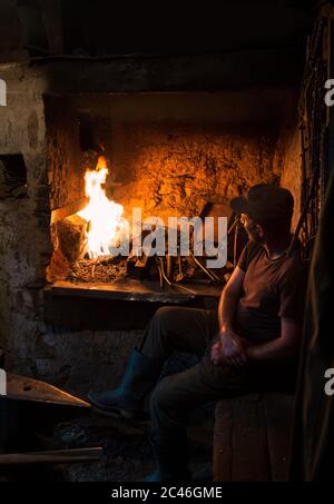 Blacksmith forge oven with hot flame. Smith heating iron piece of steel ...