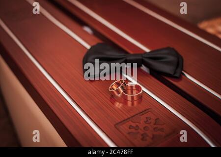 Pair of gold wedding rings and neck tie on the table Stock Photo - Alamy
