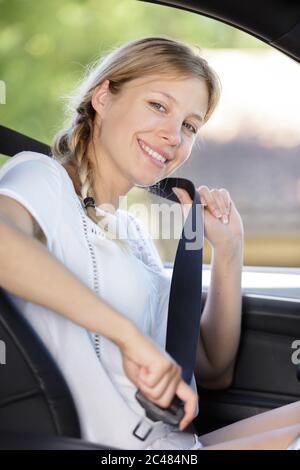 Smiling woman fastening seatbelt in car, prioritizing road trip safety ...