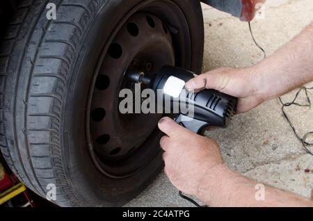 mechanic with screwdriver changing car tire Stock Photo - Alamy