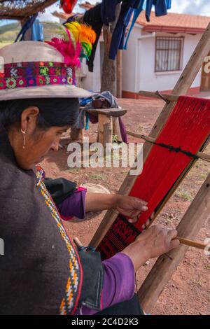 Bolivian indigenous Jalq'a woman weaving a textile with her daughter ...