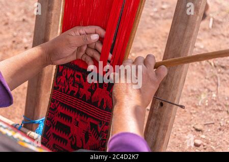 Bolivian indigenous Jalq'a woman weaving a textile with her daughter ...