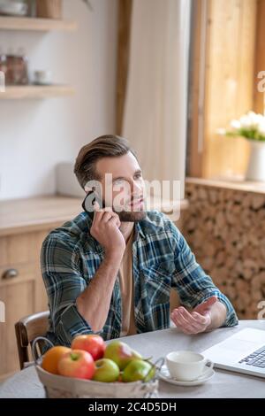 Thoughtful young bearded man with laptop at table in kitchen Stock ...