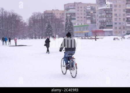 A person rides a bike down a snow-covered road during a winter storm Saturday, Jan. 24, 2026, in ...