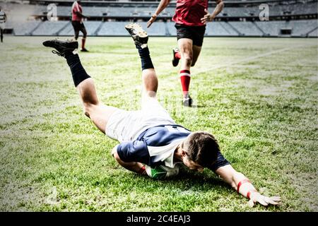Digital composite image of rugby player jumping with the ball to score ...