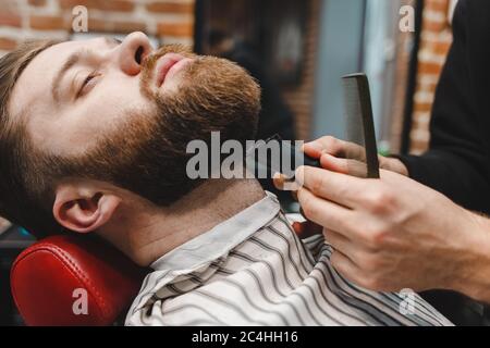 Barber master cuts beard to a brutal guy Stock Photo - Alamy
