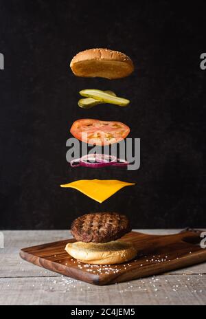 Classic beef burger floating with ingredients broken down in parts on ...