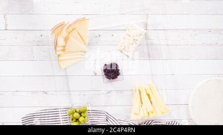 Flat lay. Step by step. Arranging cheese platter with fresh fruits ...