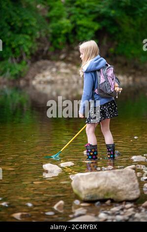 Blonde girl wading in the river and wearing a western hat, a white t ...
