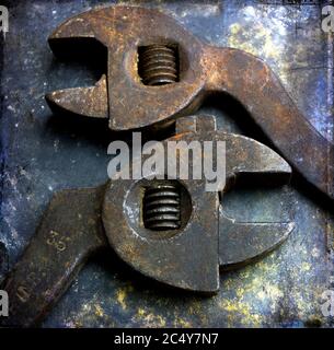 Two old rusty adjustable wrench crossed over each other on plain ...