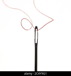 Thread passing through needle eye, close up Stock Photo - Alamy