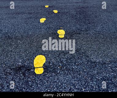 Yellow footprint signs on an asphalt road for pedestrian. Symbol of ...