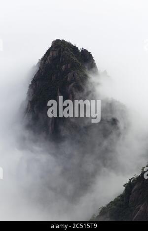A scenic view of Huangshan mountain covered with trees against blue sky ...