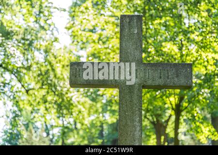 Closeup shot of a stone cross as a grave with the letters "R.I.P" on it ...